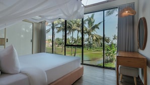 Quarto com uma cama grande, mesa de cabeceira de madeira, janela ampla com vista para palmeiras e um campo de arroz, e teto com tecido pendurado.