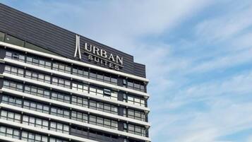 Um edifício moderno de hotel com uma placa na fachada que diz 'URBAN SUITES'.