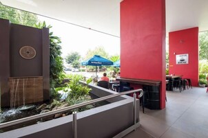 Espaço interno com piscina, parede vermelha e placa indicando um restaurante.