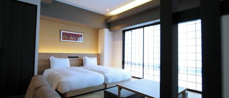 Quarto de hotel moderno com uma cama grande, um sofá, uma mesa pequena e uma janela ampla que oferece uma vista.