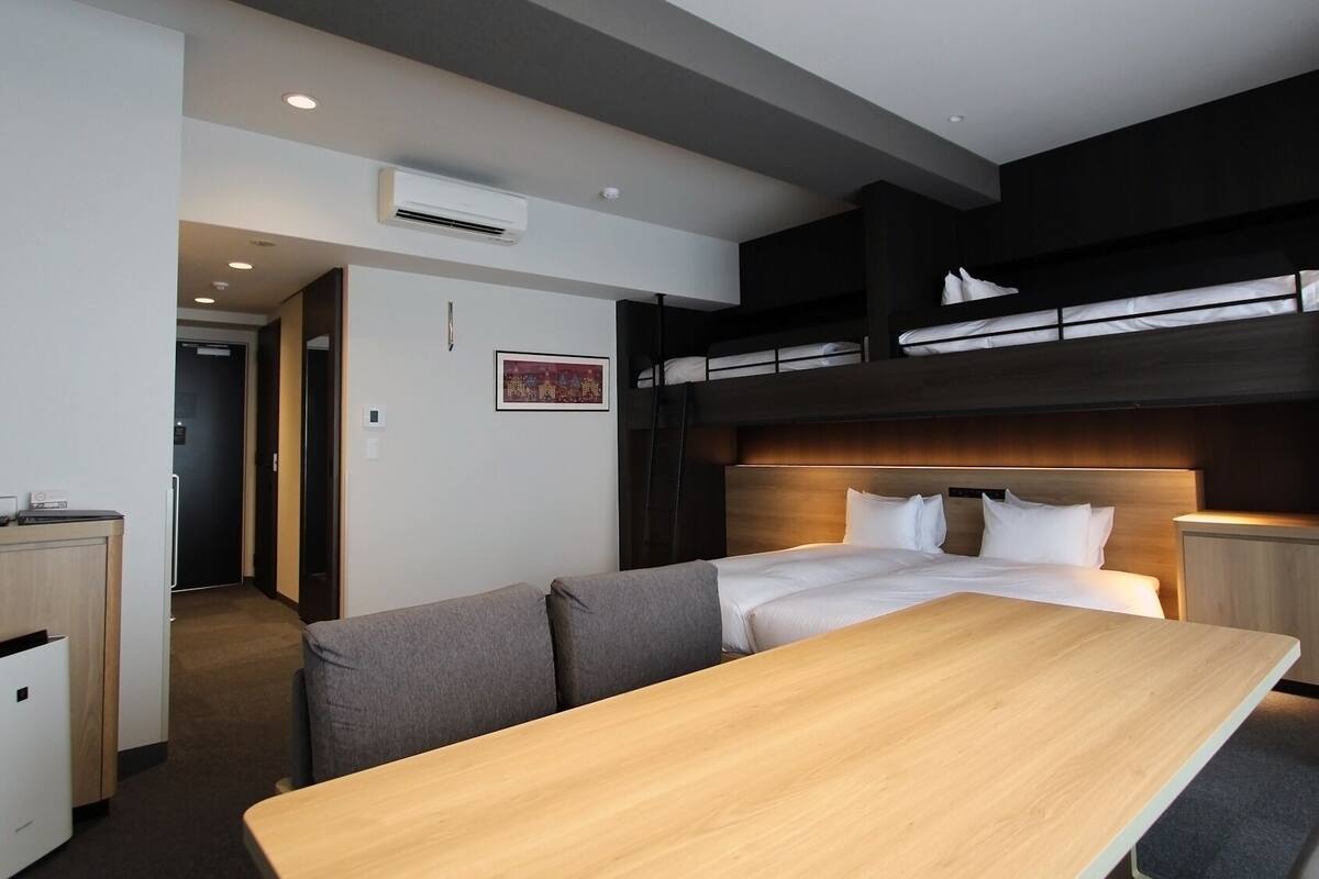 Quarto com beliche, mesa de madeira, sofá e escrivaninha com cadeira.