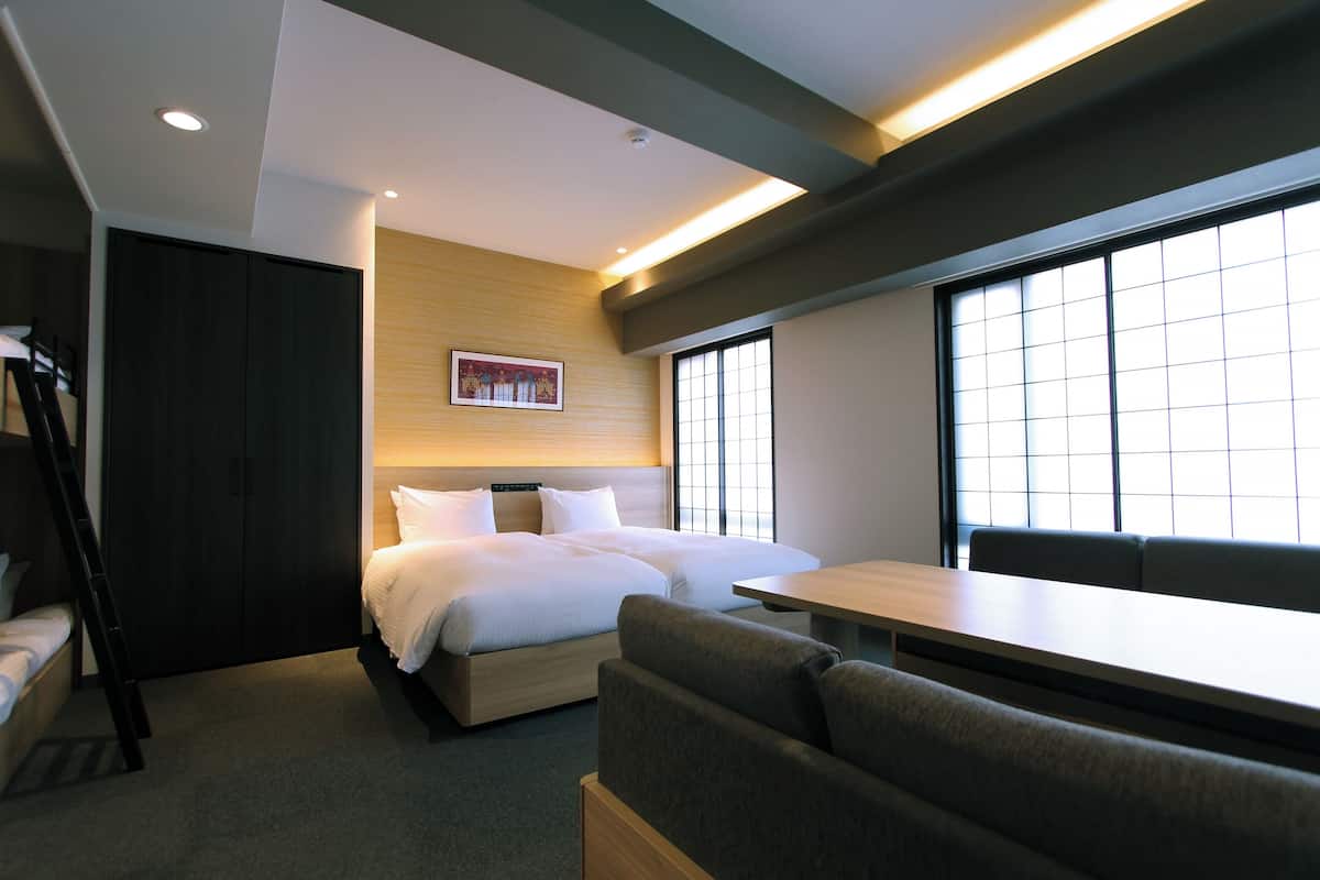 Quarto de hotel moderno com cama, sofá, mesa e janela.
