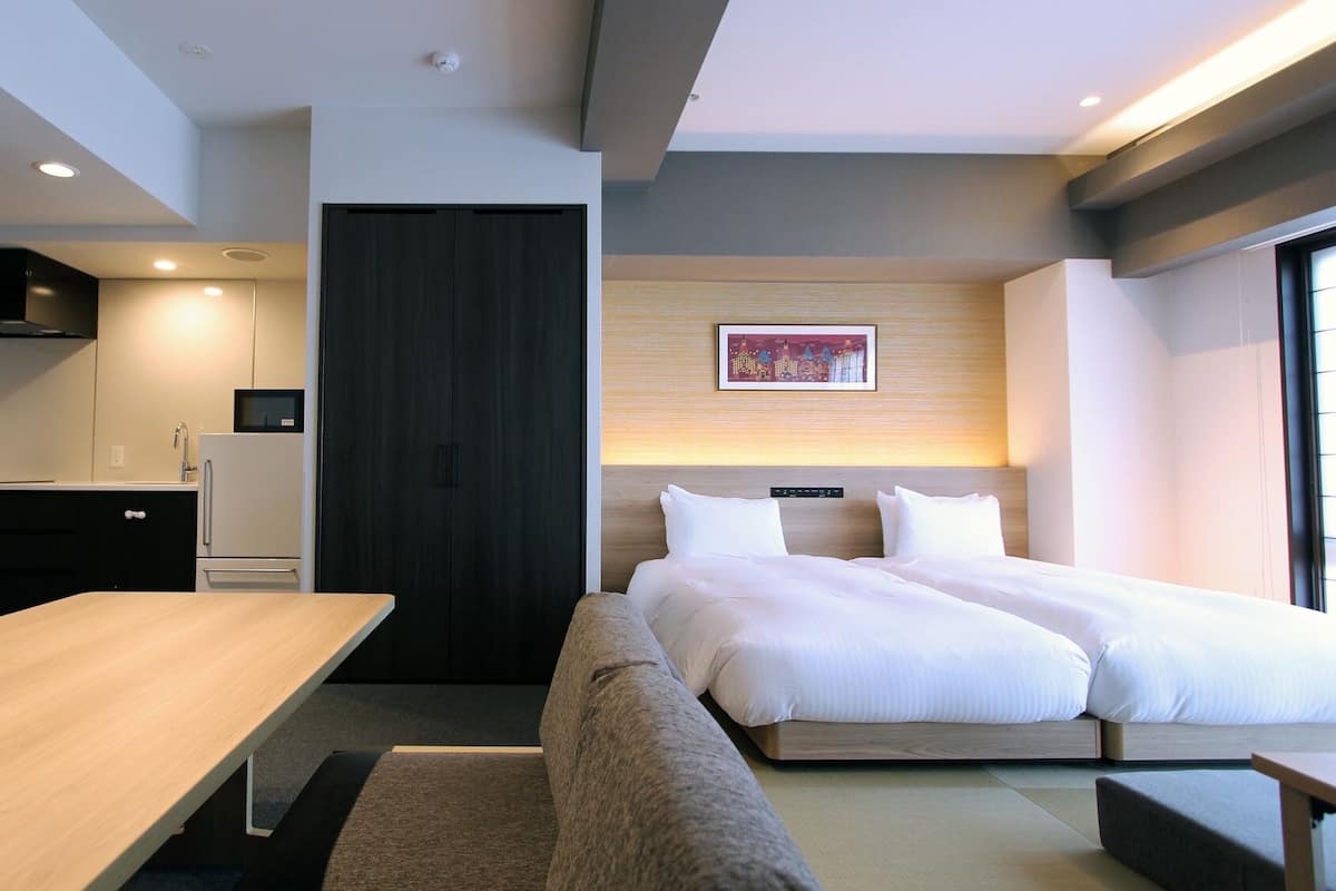 Quarto de hotel moderno com cama, escrivaninha, cozinha compacta e vista para a cidade.