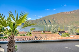 Vista de um lago com edifícios e uma montanha ao fundo.