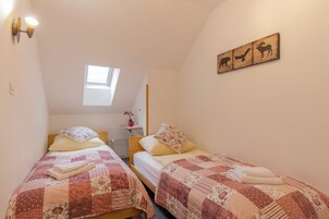 Quarto com duas camas, um claraboia, uma obra de arte na parede e uma pequena mesa com um vaso de planta.