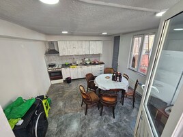Uma cozinha compacta com área de refeições, apresentando uma mesa redonda com cadeiras, fogão embutido e armários.