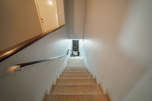 Uma escada com corrimão, levando a uma porta no topo.