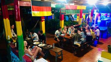 Um grupo de pessoas jantando em um restaurante com pilares coloridos e piso de azulejos.