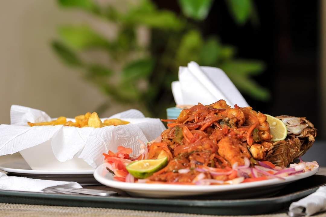Prato de comida com camarões, legumes, uma fatia de limão e batatas fritas.
