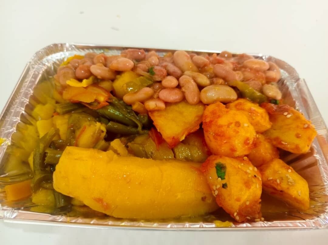 Uma refeição em recipiente de alumínio com diversos vegetais e feijão.