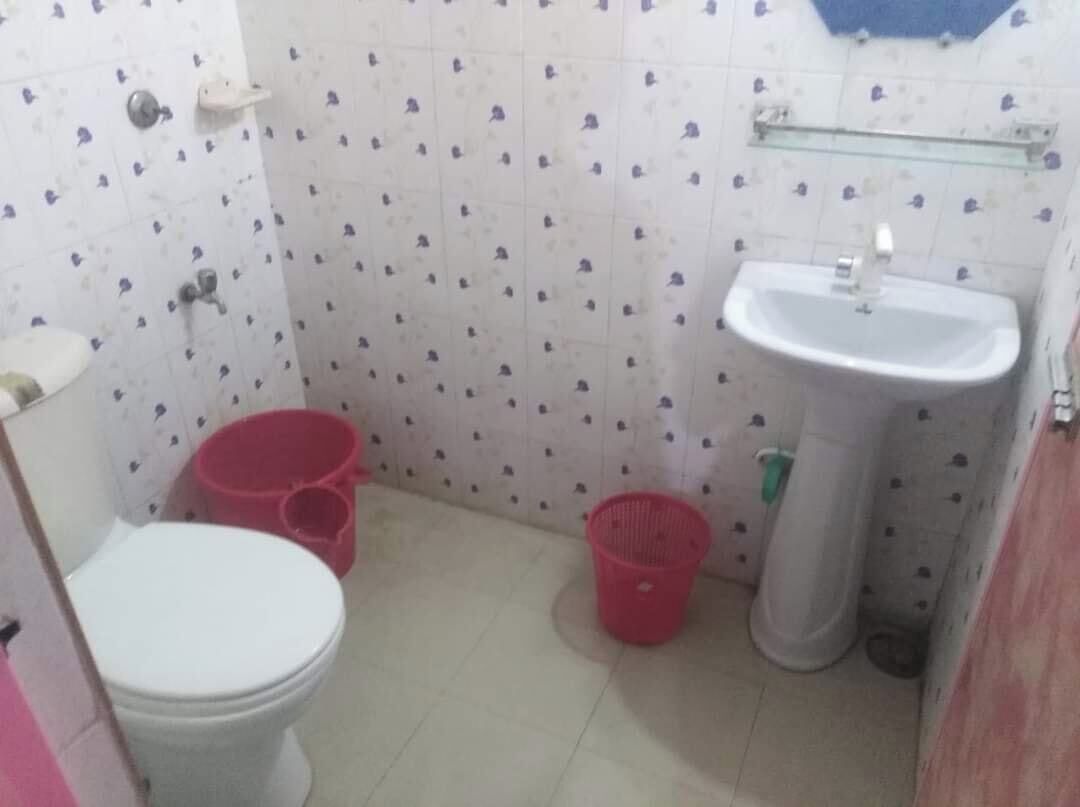 Casa de banho pequena com sanita, lavatório e duas cestas vermelhas.