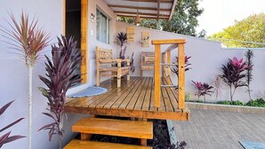 Um deck de madeira com pérgola, área de estar externa e plantas em vasos.