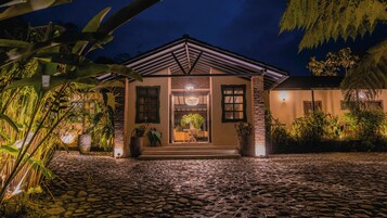Um edifício com entrada em pedra, uma área central aberta com mesa e cadeiras, e interior bem iluminado.