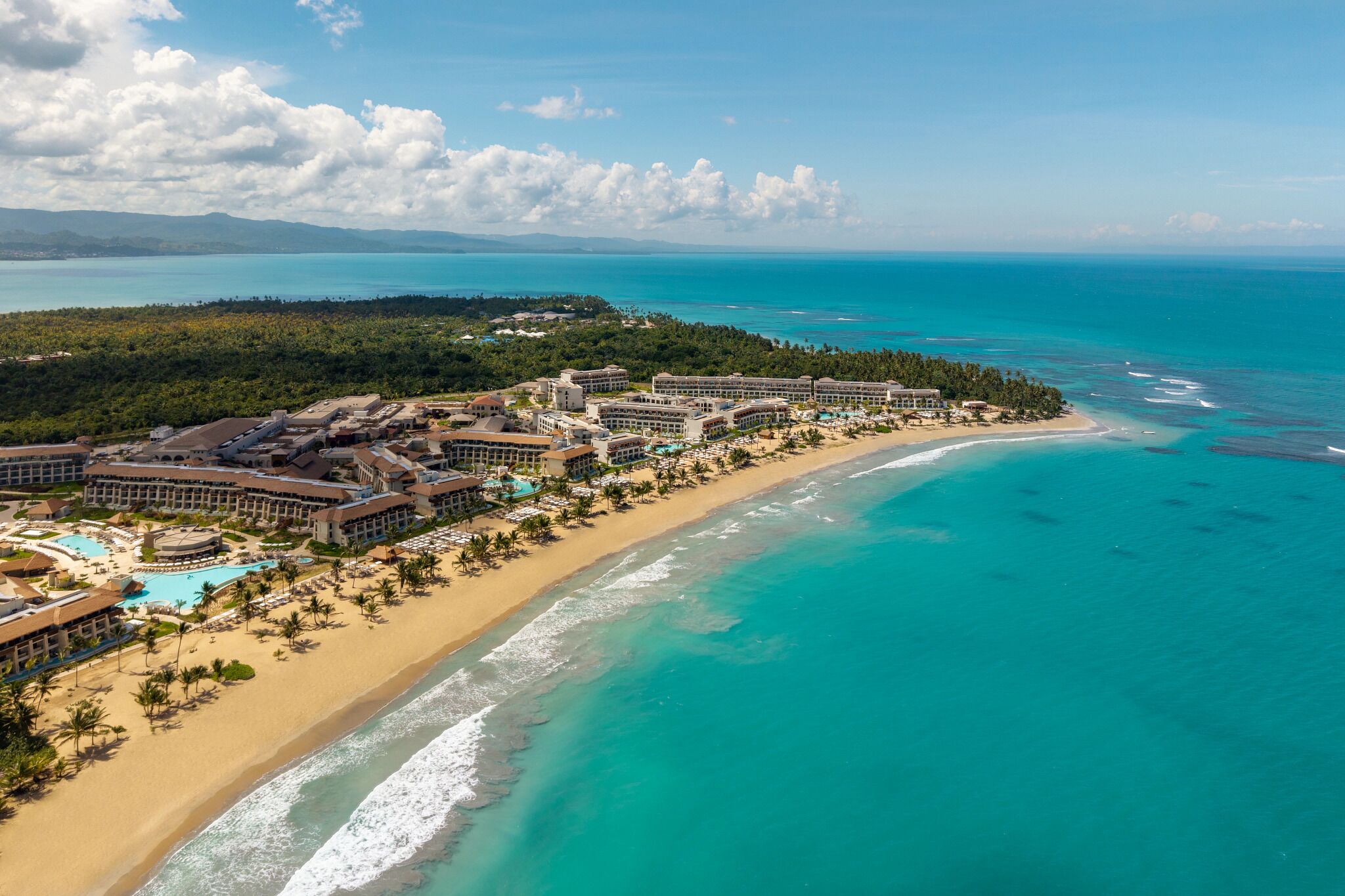 Um resort com vários edifícios, uma praia e vista clara para o oceano.