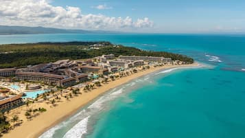 Um resort com vários edifícios, uma praia e vista clara para o oceano.