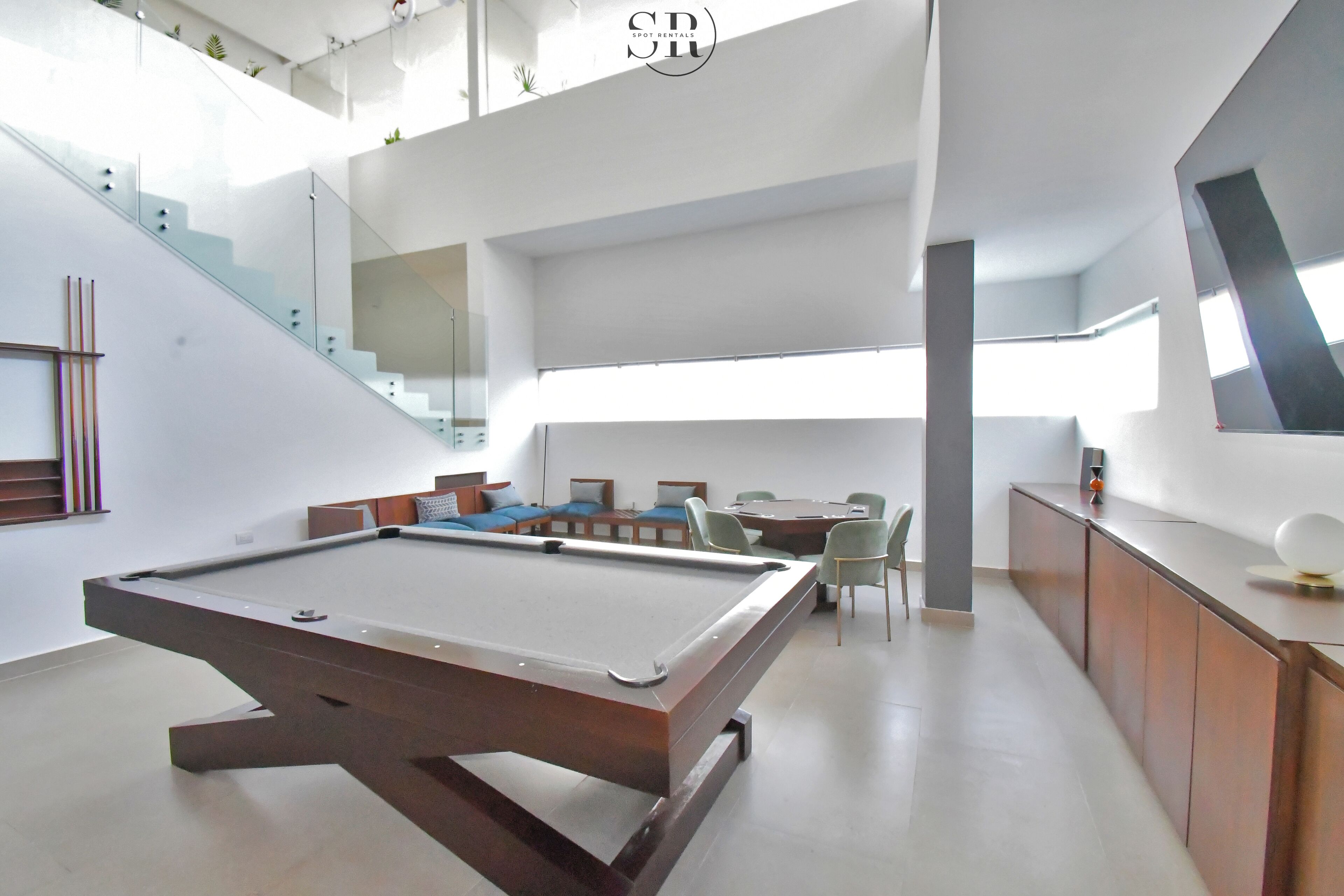 Um interior moderno com mesa de bilhar, área de estar e escada.