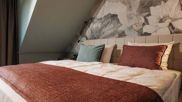 Quarto com cama, almofadas, cabeceira e parede com mural floral.