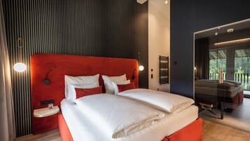 Quarto de hotel moderno com uma cama grande, uma mesinha de cabeceira, um espelho e vista para o exterior.