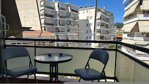 Varanda com duas cadeiras e uma pequena mesa, com vista para uma fileira de edifícios altos com varandas.