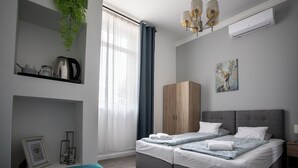 Quarto moderno com cama de casal, guarda-roupa, mesa de cabeceira e uma planta pendente.