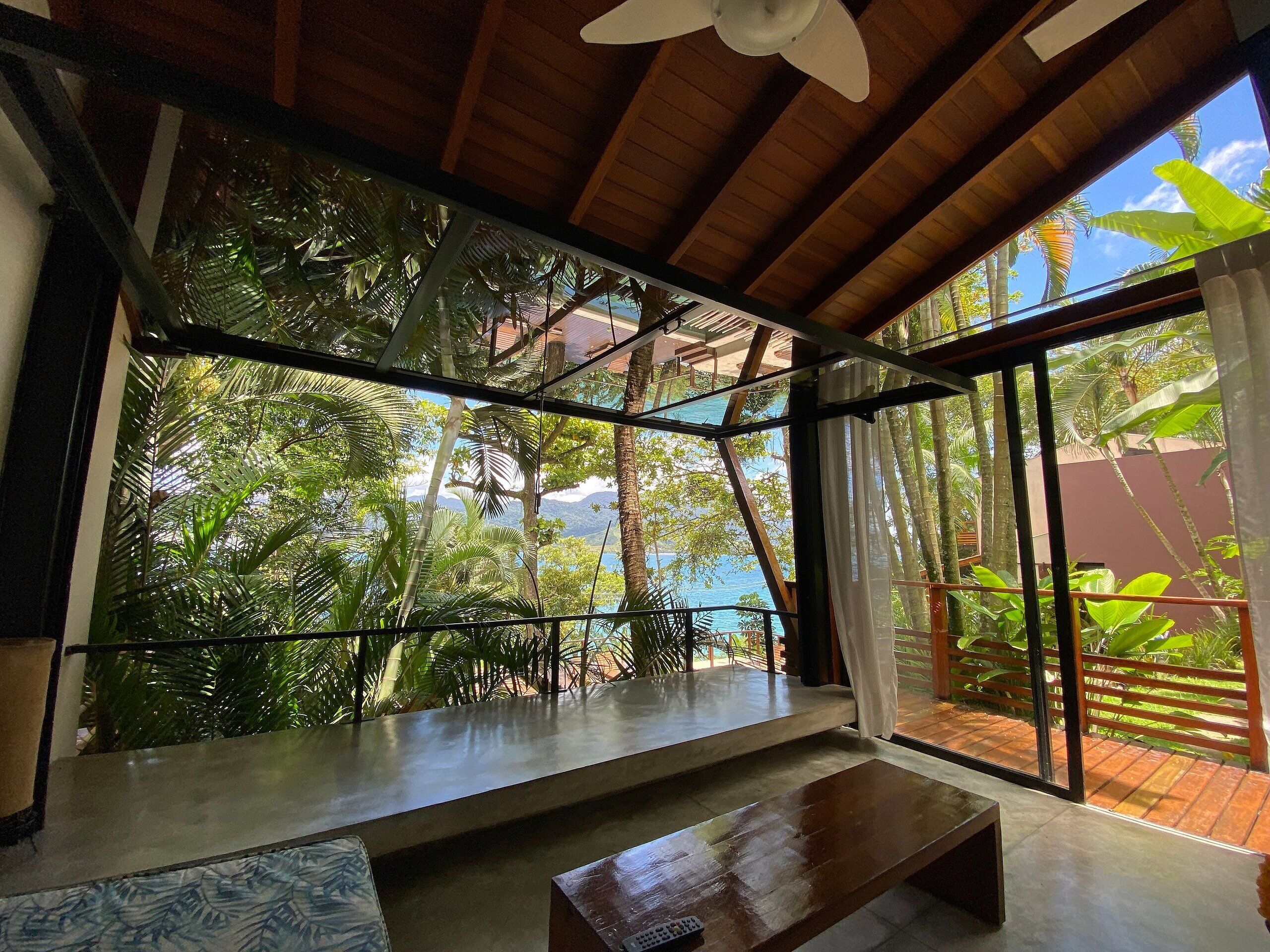 Quarto moderno com uma janela grande, teto de madeira e um banco de concreto.