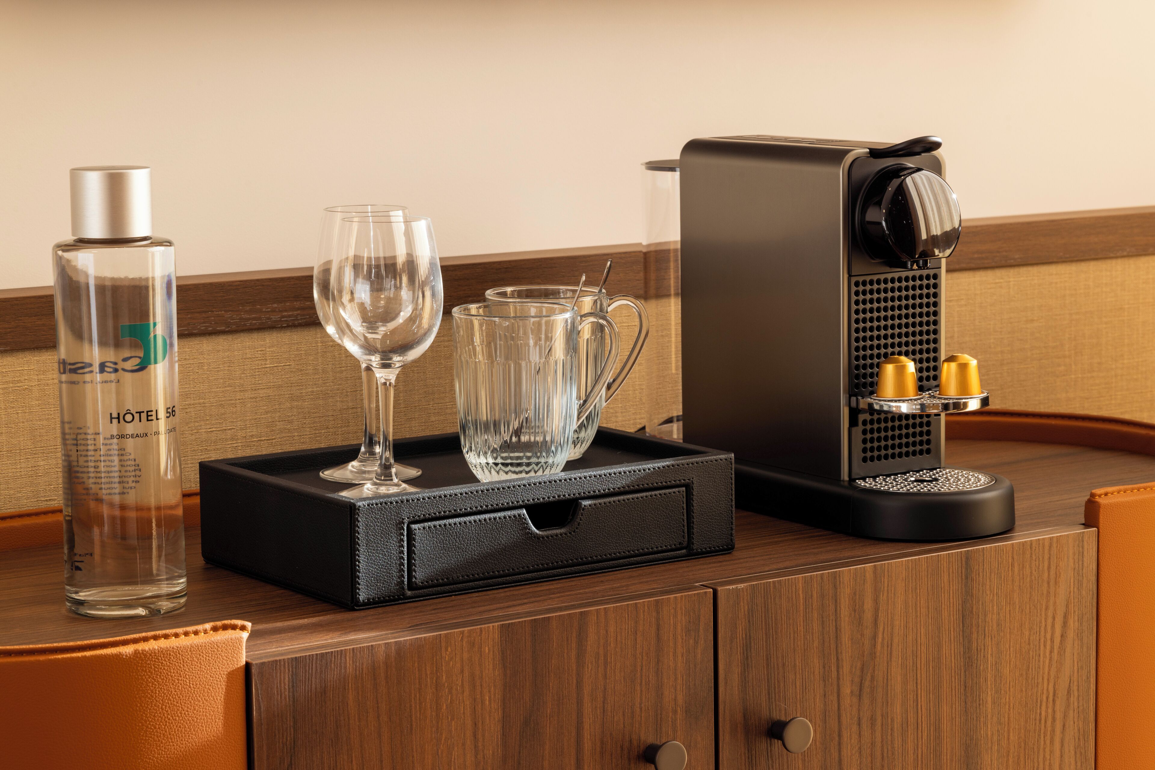 Mini-bar com uma garrafa de água, dois copos e uma máquina de café.