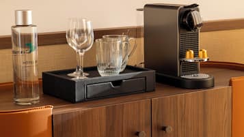 Mini-bar com uma garrafa de água, dois copos e uma máquina de café.