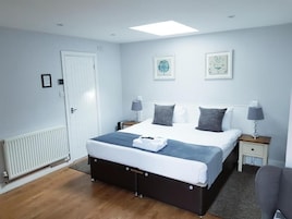 Quarto bem arrumado com cama, mesas de cabeceira e uma porta.