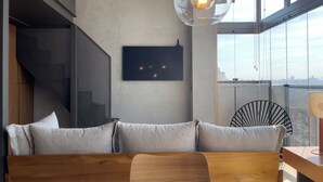 Uma sala de estar moderna com um banco de madeira, uma janela grande e um lustre.