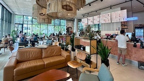 Um café moderno com assentos de couro, balcão de café e grandes janelas.