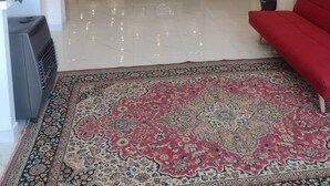 Um hall amplo com balcão de recepção, sofás vermelhos, tapete estampado e um espelho grande.