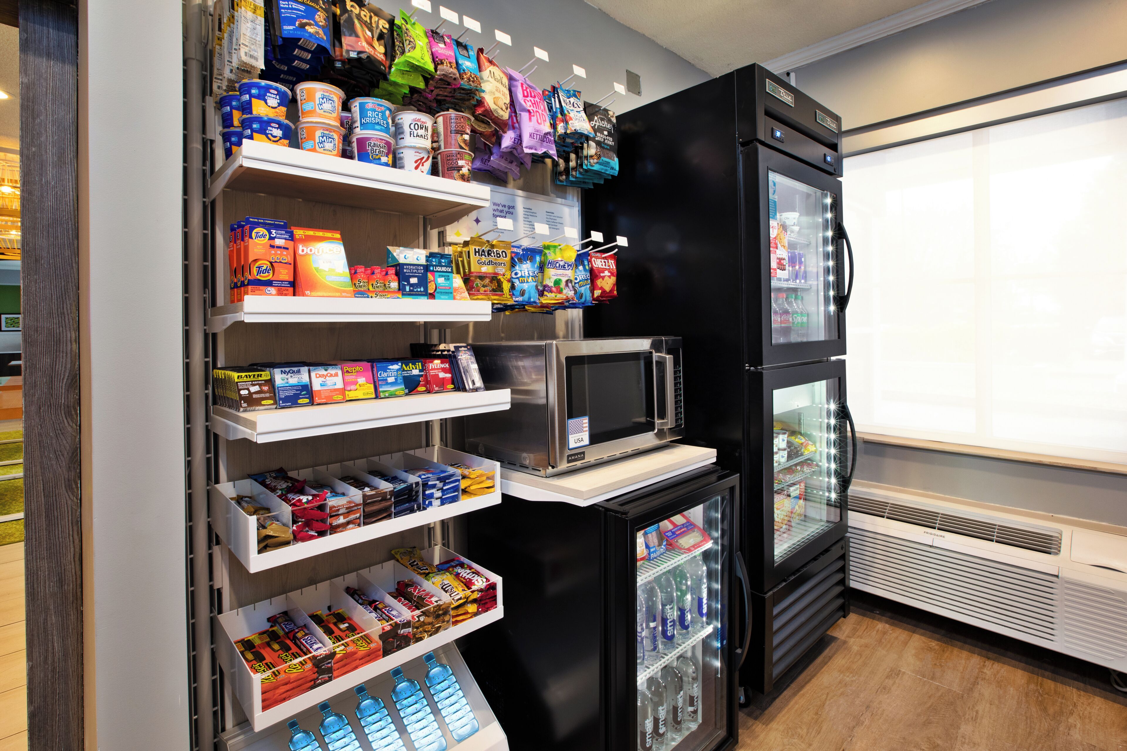 Quiosque de lanches e bebidas de autoatendimento, com seções refrigeradas e não refrigeradas, incluindo micro-ondas e refrigerador de bebidas.