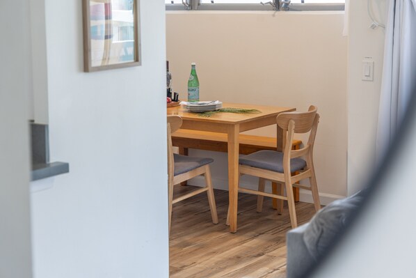 Uma área de refeições com uma mesa de madeira e duas cadeiras, uma garrafa de água e um prato de comida.
