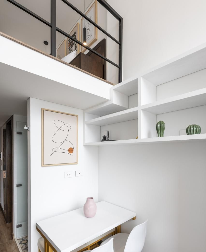 Um interior moderno com uma escrivaninha branca, um vaso rosa e uma obra de arte abstrata emoldurada.