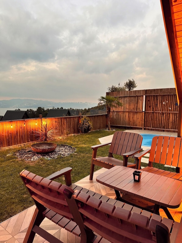Quintal com deck de madeira, piscina e vista para o horizonte da cidade.