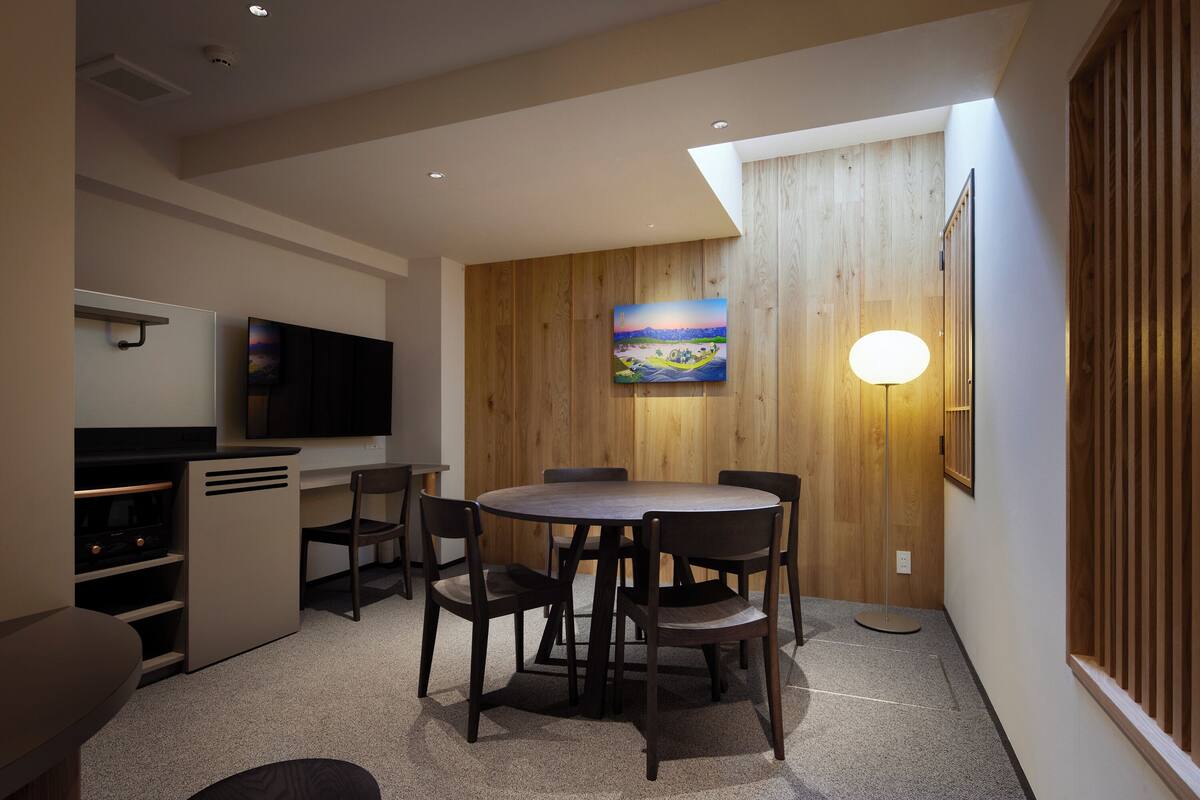Cozinha moderna com área de jantar, paredes de painel de madeira, um quadro e uma mesa redonda com cadeiras.