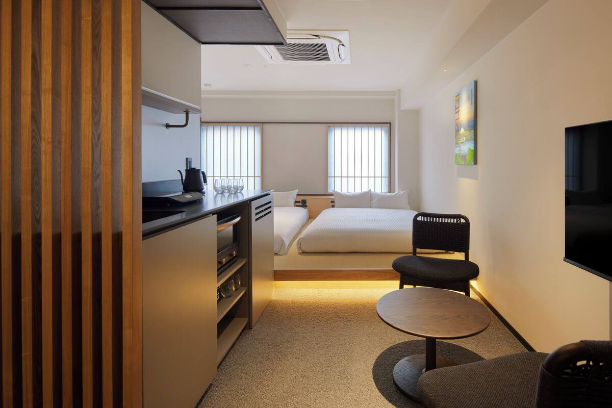 Quarto de hotel compacto com cozinha compacta, cama, área de estar e televisão.