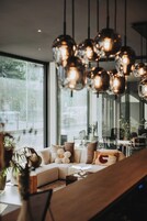 Um interior moderno com um sofá, uma mesa de madeira e luminárias pendentes.