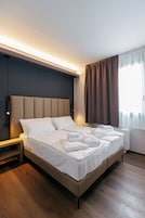 Quarto de hotel moderno com cama, mesa de cabeceira e vista para o exterior.