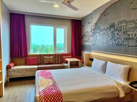 Quarto de hotel com uma cama, área de estar com vista e um mural na parede.