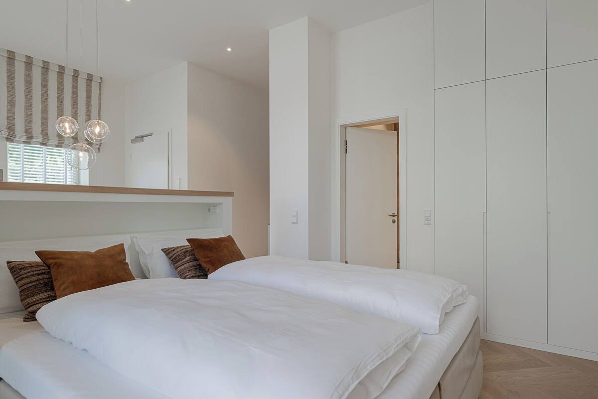 Um quarto moderno com uma cama grande, um guarda-roupa e um espelho.