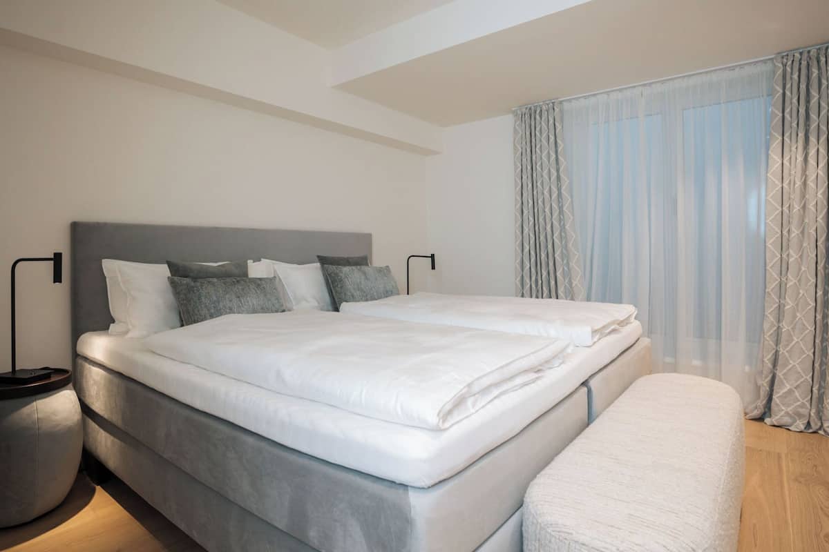 Quarto moderno com uma cama grande, mesas de cabeceira e luminária.