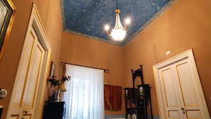 Um corredor com teto estrelado, um candelabro e carpete estampado.