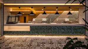 Uma área de recepção moderna com piso em azulejo, balcão com vitrine de vidro e iluminação pendente.