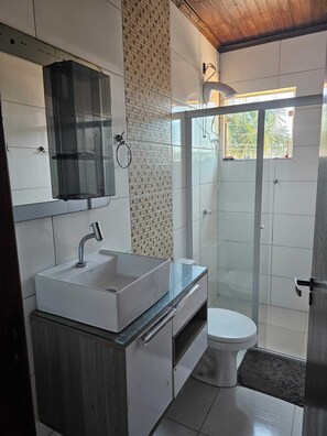 Uma casa de banho moderna com uma grande pia, sanita e zona de duche.