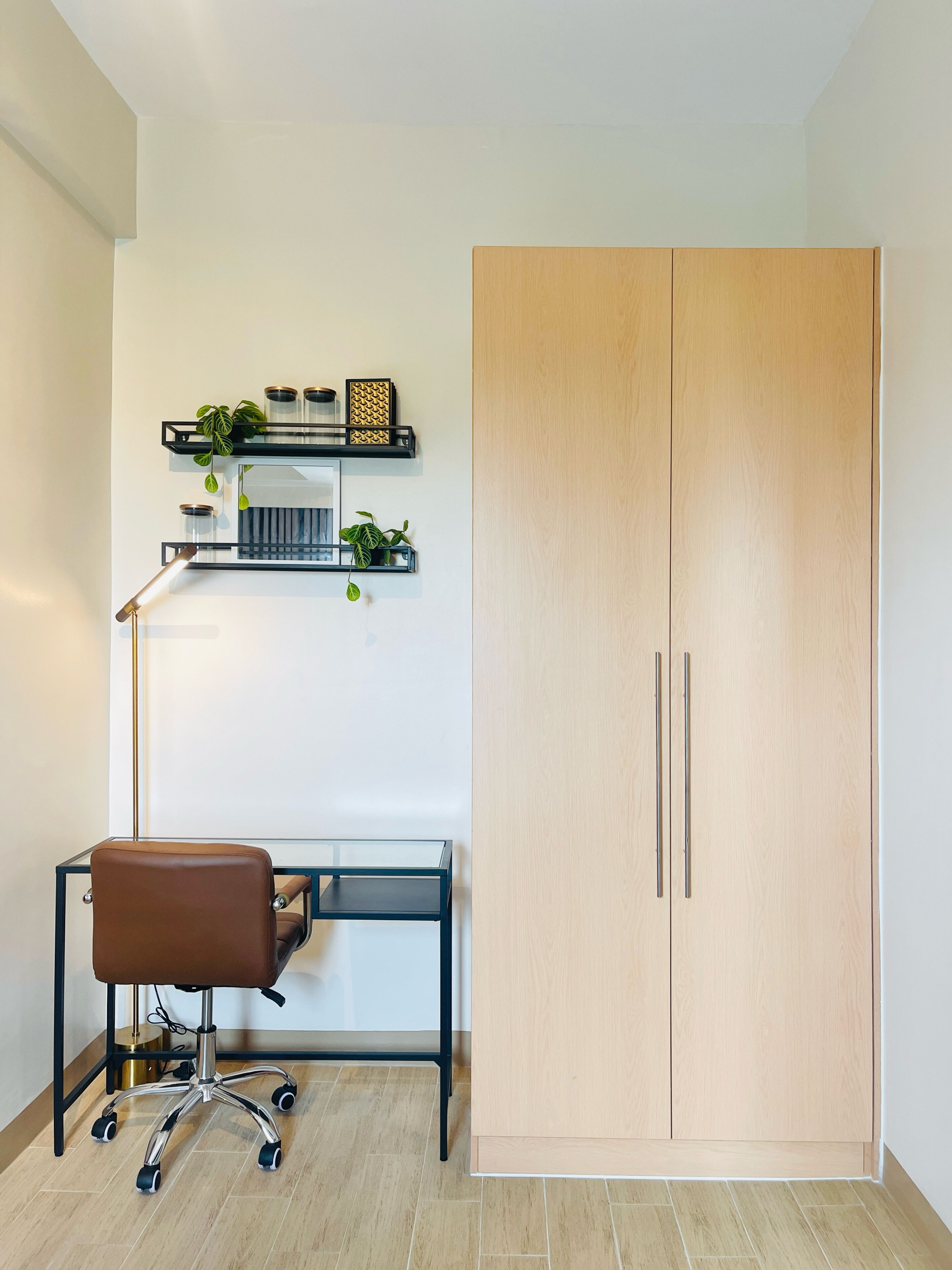 Um espaço de escritório moderno com escrivaninha, cadeira, estantes com plantas e um guarda-roupa grande.