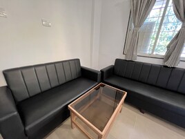 Uma sala de estar moderna com dois sofás pretos e uma mesa de centro de vidro.