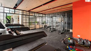 Uma academia moderna com equipamentos de ginástica, janelas amplas e uma parede de destaque vermelha.