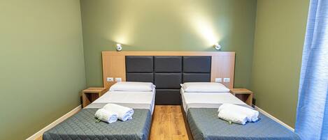 Quarto duplo com duas camas, cabeceiras de madeira e mesas de cabeceira com luminárias.