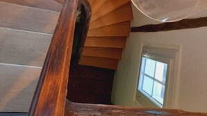Escada espiral de madeira com corrimão de madeira e luminária pendente.